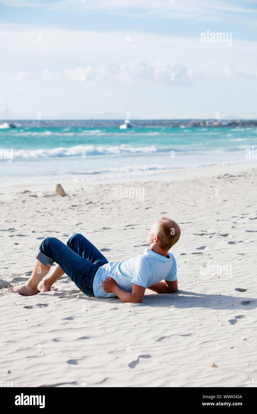 Young man relaxing on the beach by the water in summer Stock Photo - Alamy