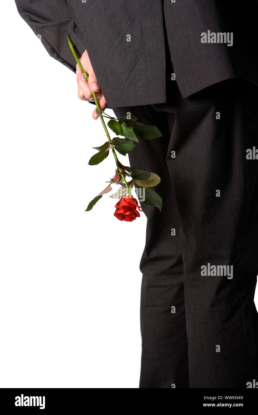 Man holding a red rose behind his back Stock Photo - Alamy