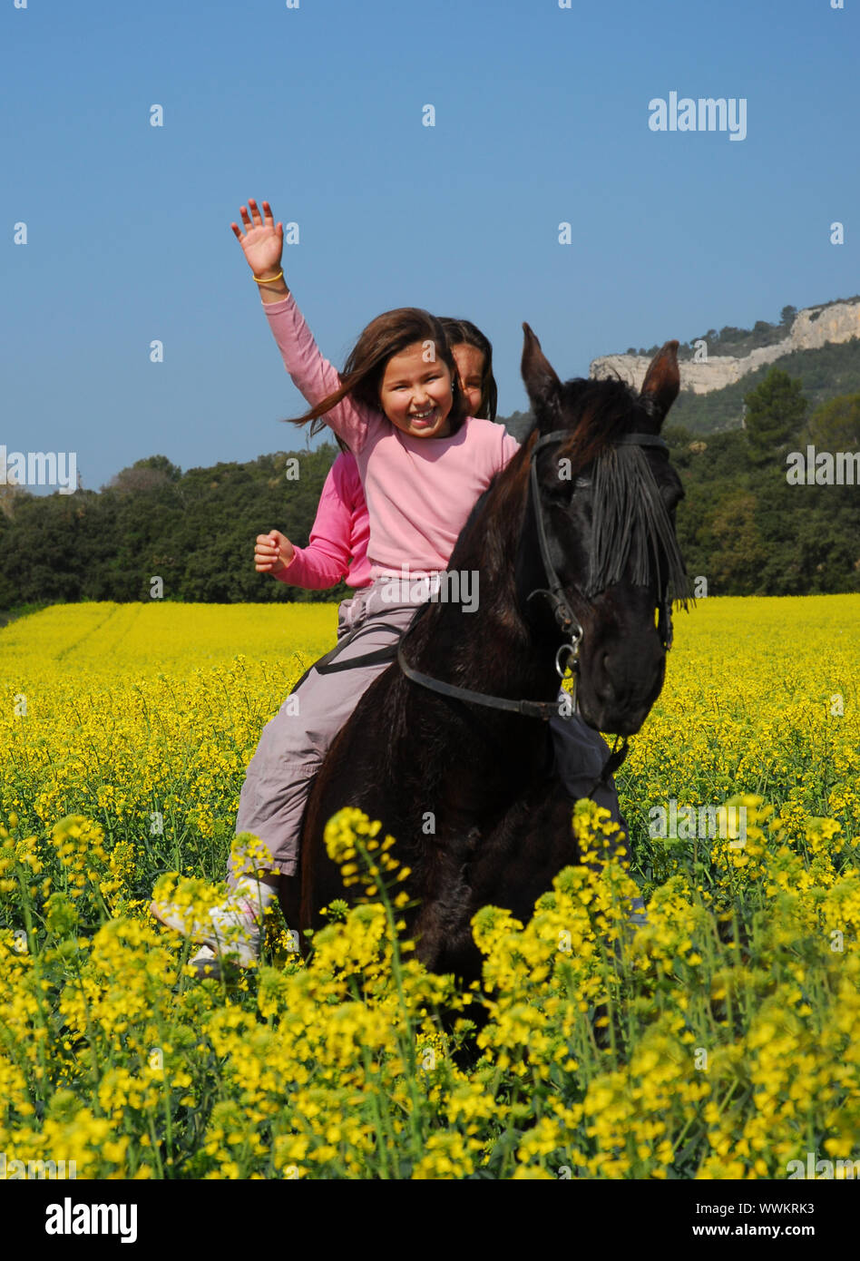 twins sisters horseback riding a black stallion Stock Photo - Alamy