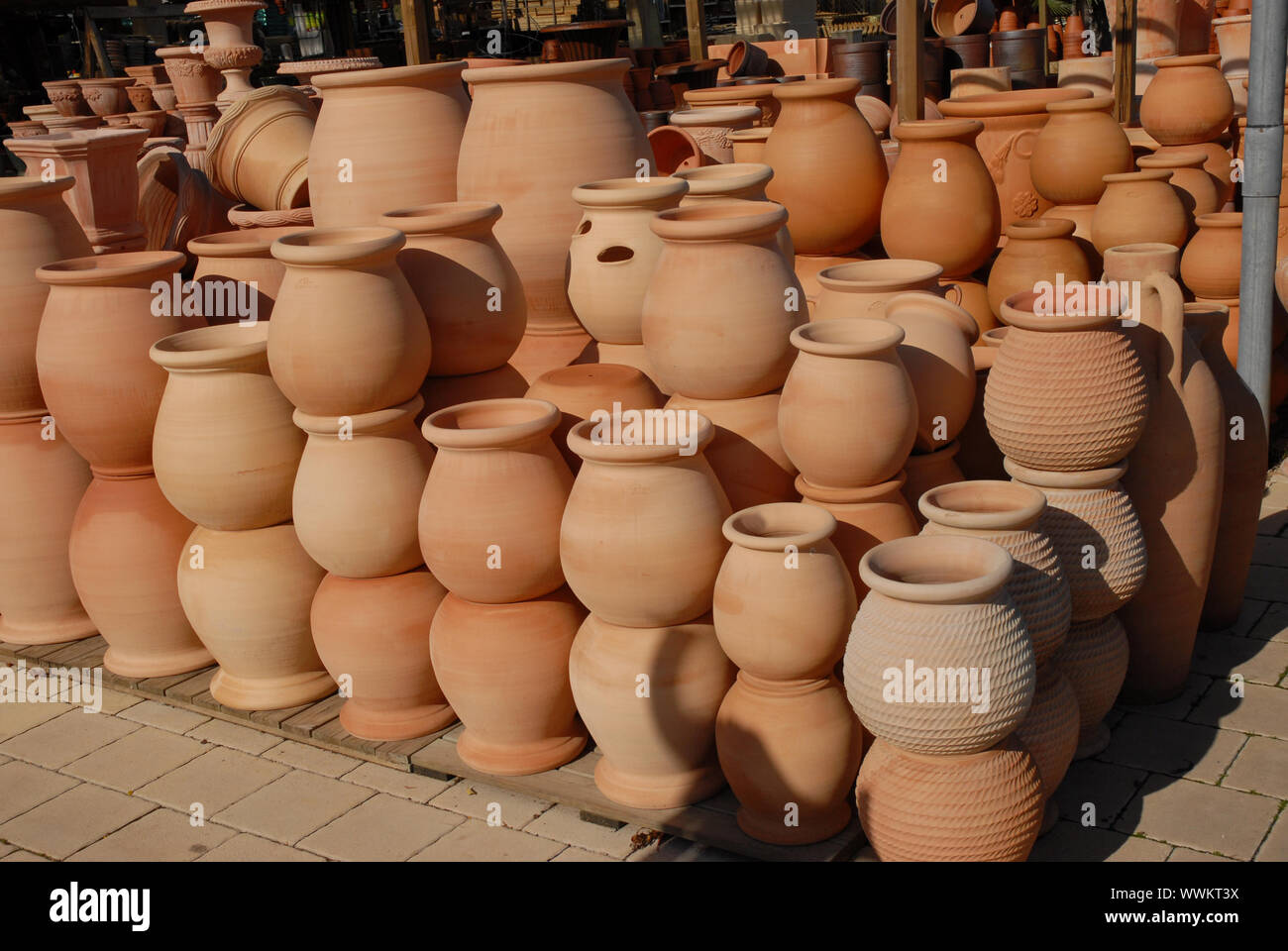 various sizes and shapes of terra cotta pots stacked on a potting bench ...