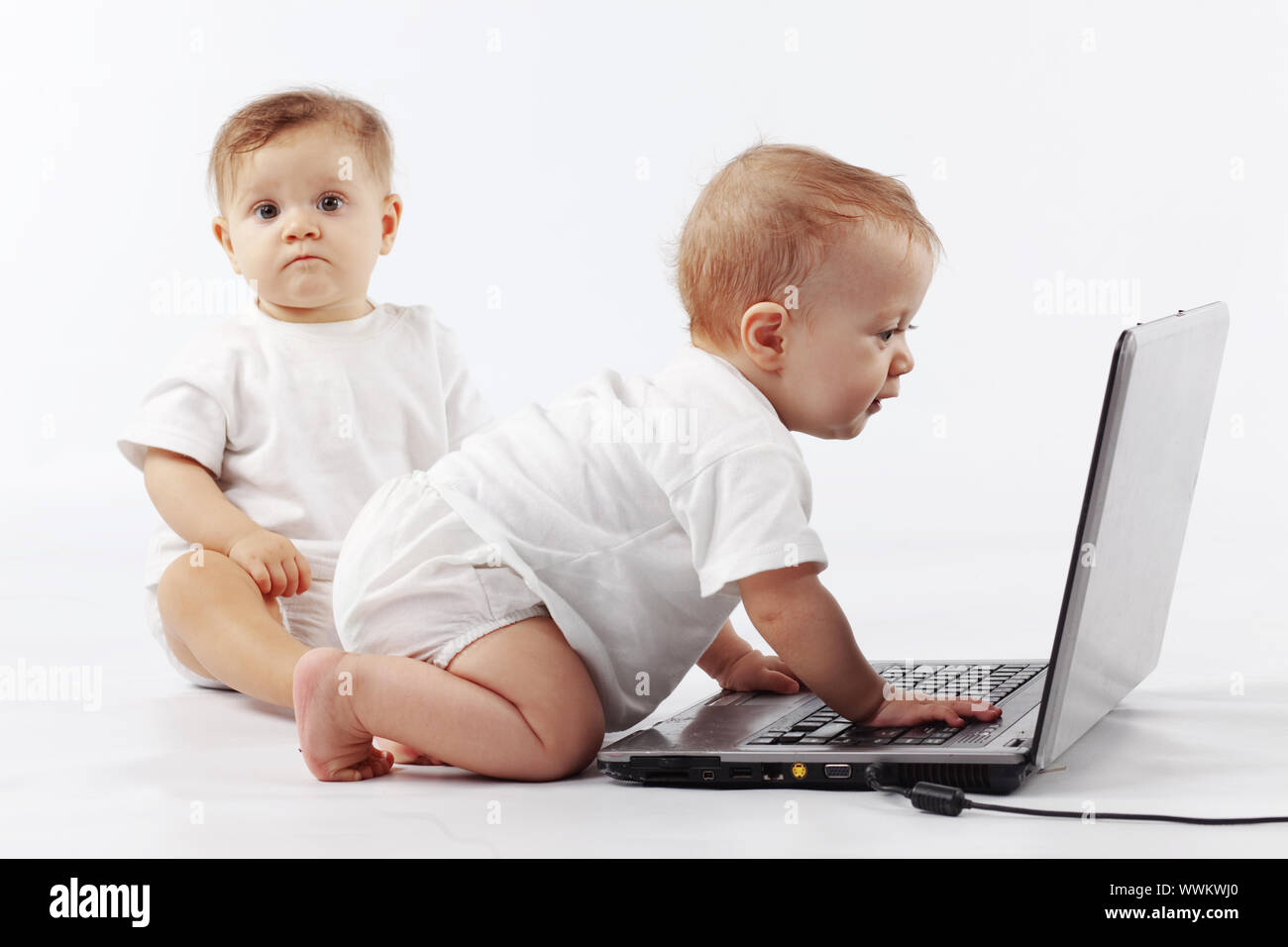 Two cute babies playing with laptop Stock Photo - Alamy