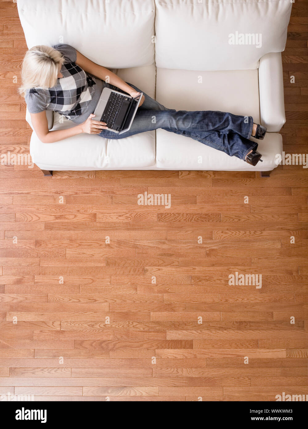 Full length overhead view of woman reclining on white couch and using a ...