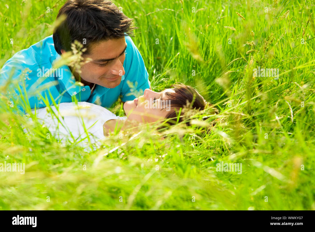 young couple laying down in meadow and hugging Stock Photo - Alamy