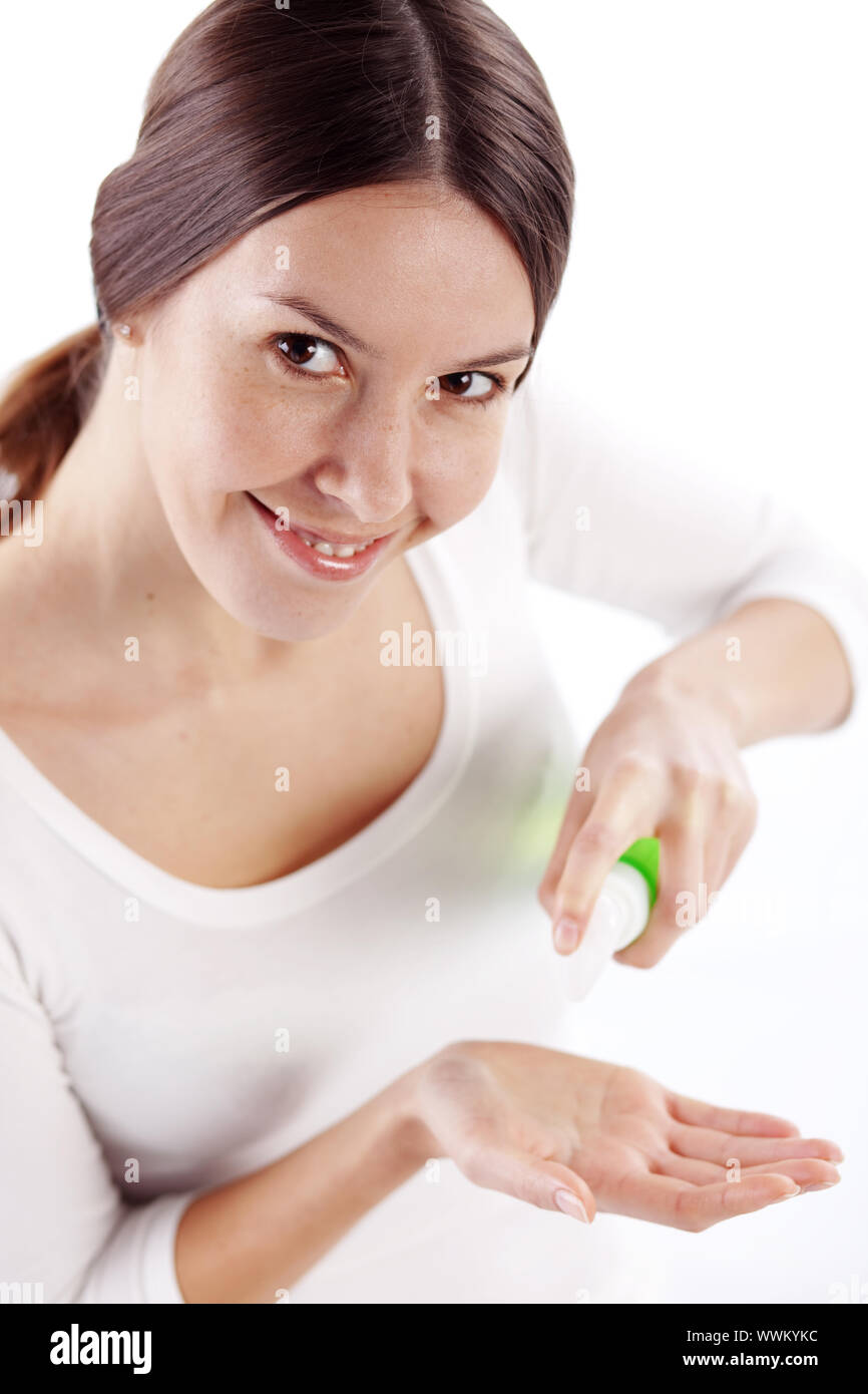 Portrait of beautiful young woman applying face cosmetic products on ...