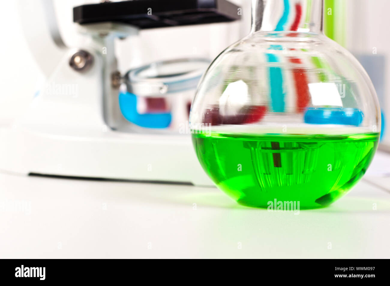 lab bottle with green liquid, in the background microscope and other ...