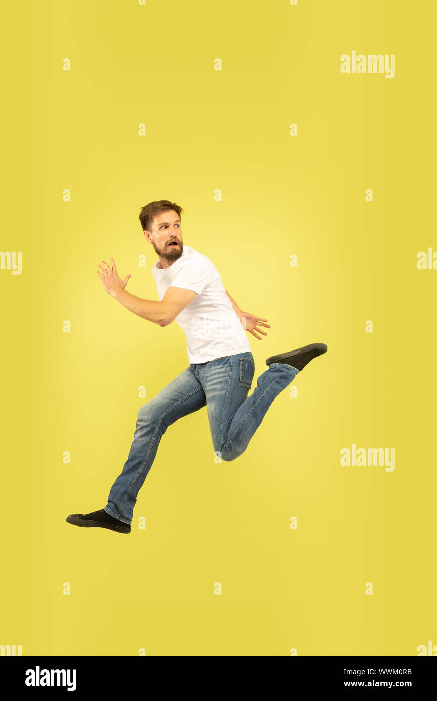Full length portrait of happy jumping man isolated on yellow background ...