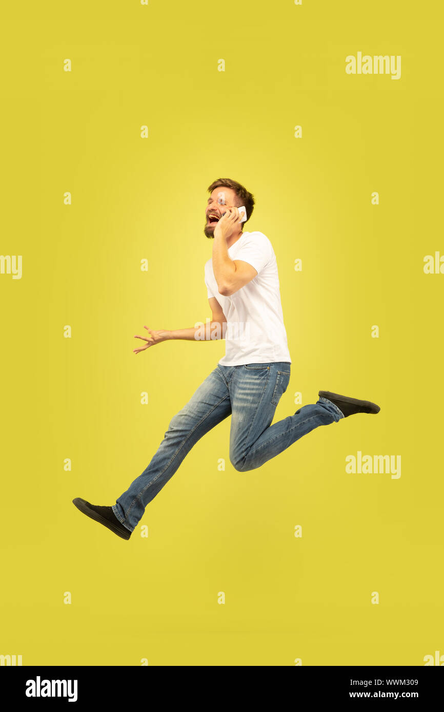 Full length portrait of happy jumping man isolated on yellow background ...