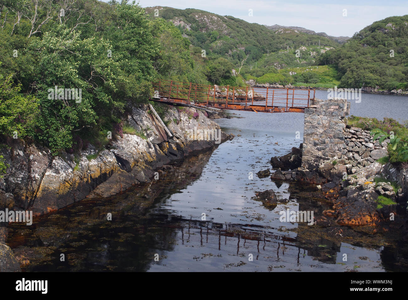 A view of a broken rickety footbridge over the end of Loch Roe ...