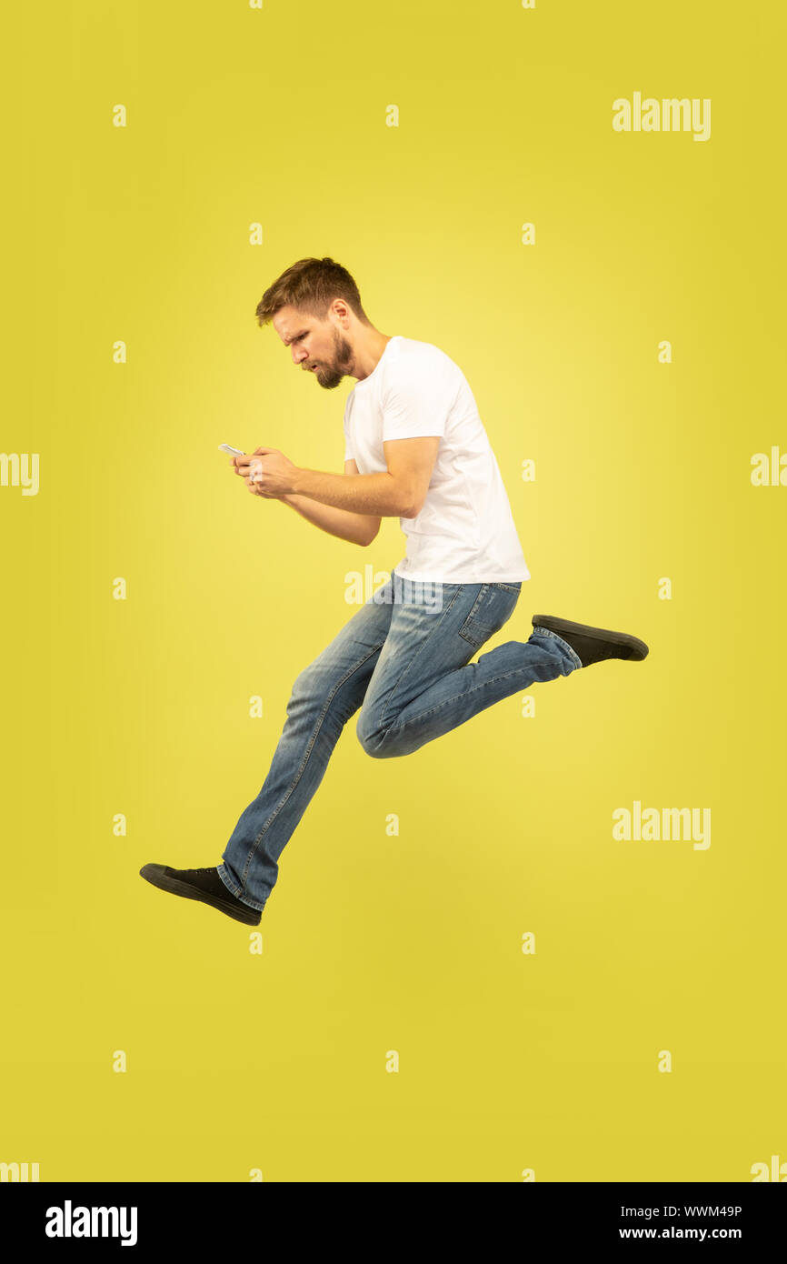 Full length portrait of happy jumping man isolated on yellow background ...