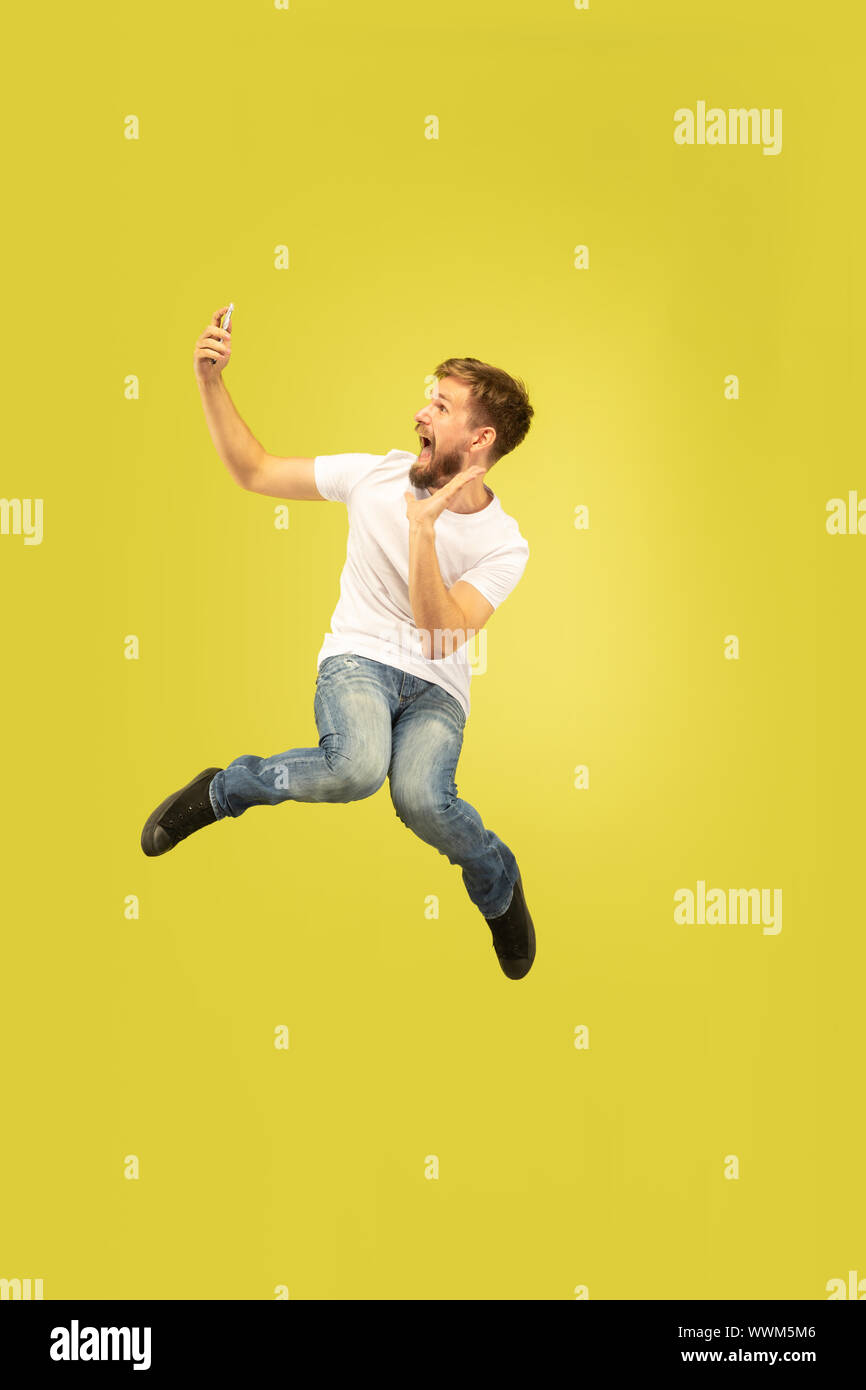 Full length portrait of happy jumping man isolated on yellow background ...
