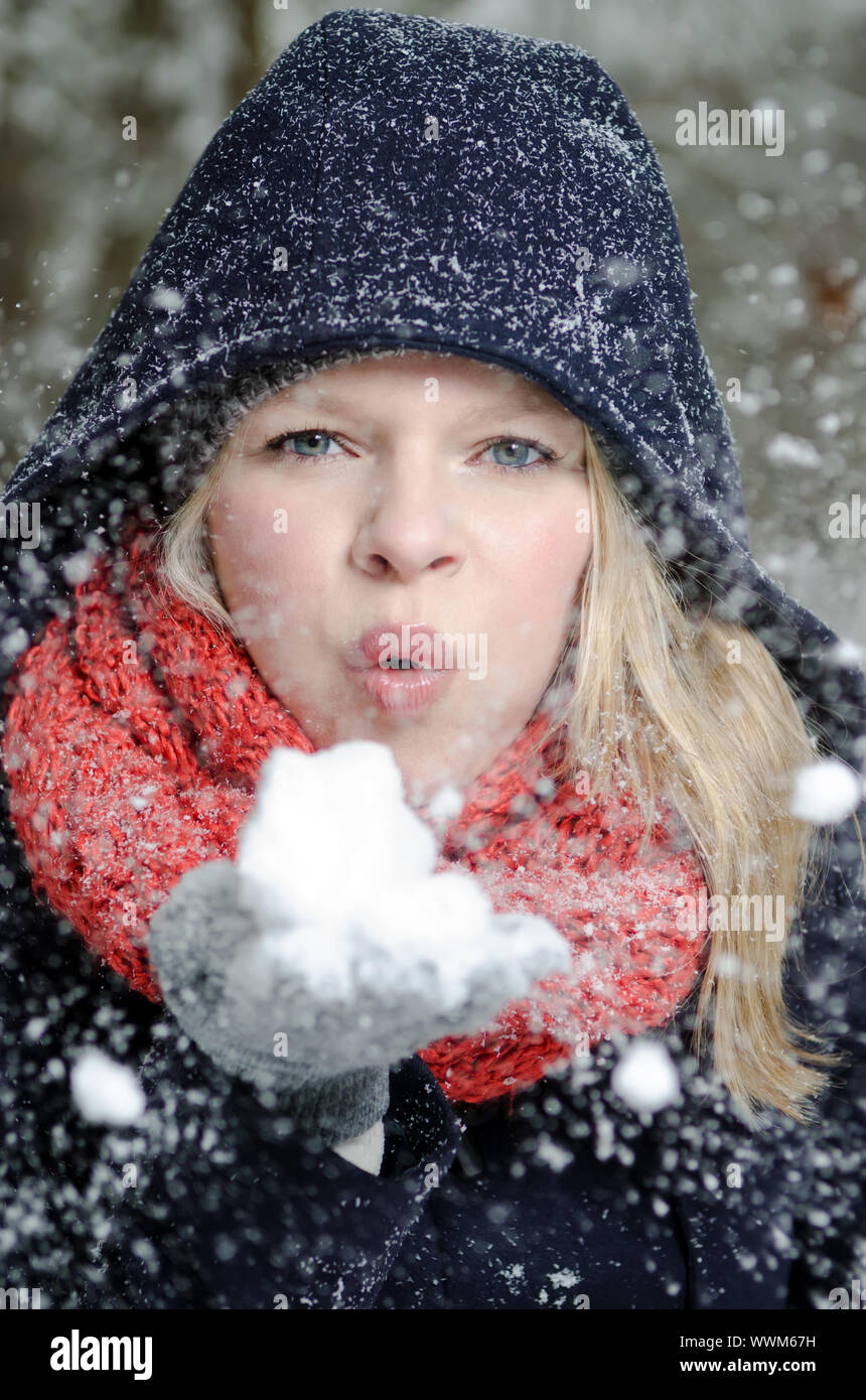 young blonde woman blowing into a handful of snow Stock Photo - Alamy