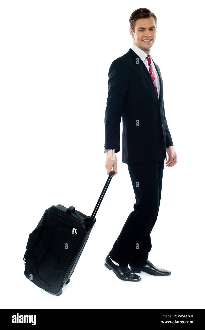 Handsome businessman dragging trolley bag as he walks Stock Photo - Alamy