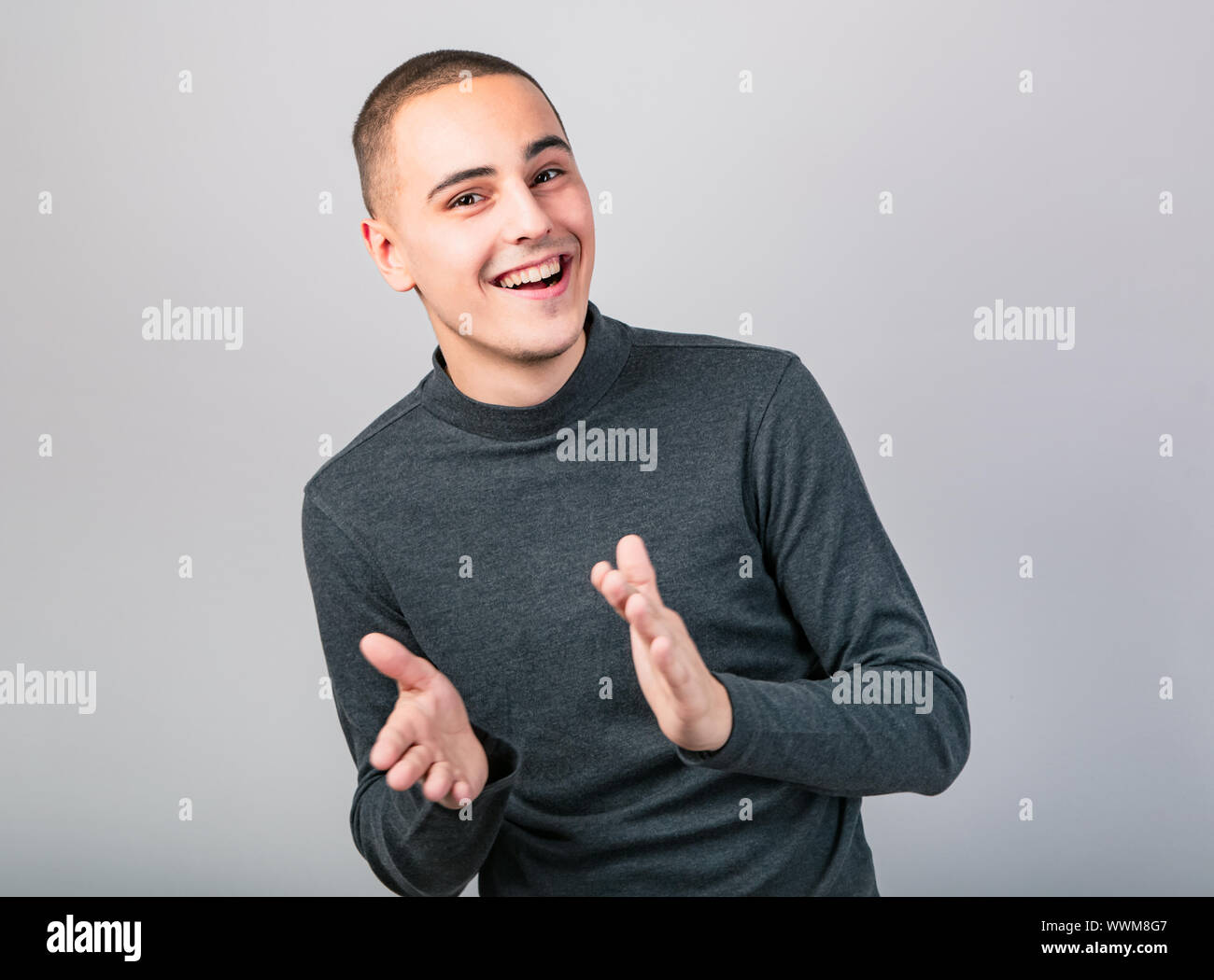 Happy smiling young man clapping one's hands on blue background ...