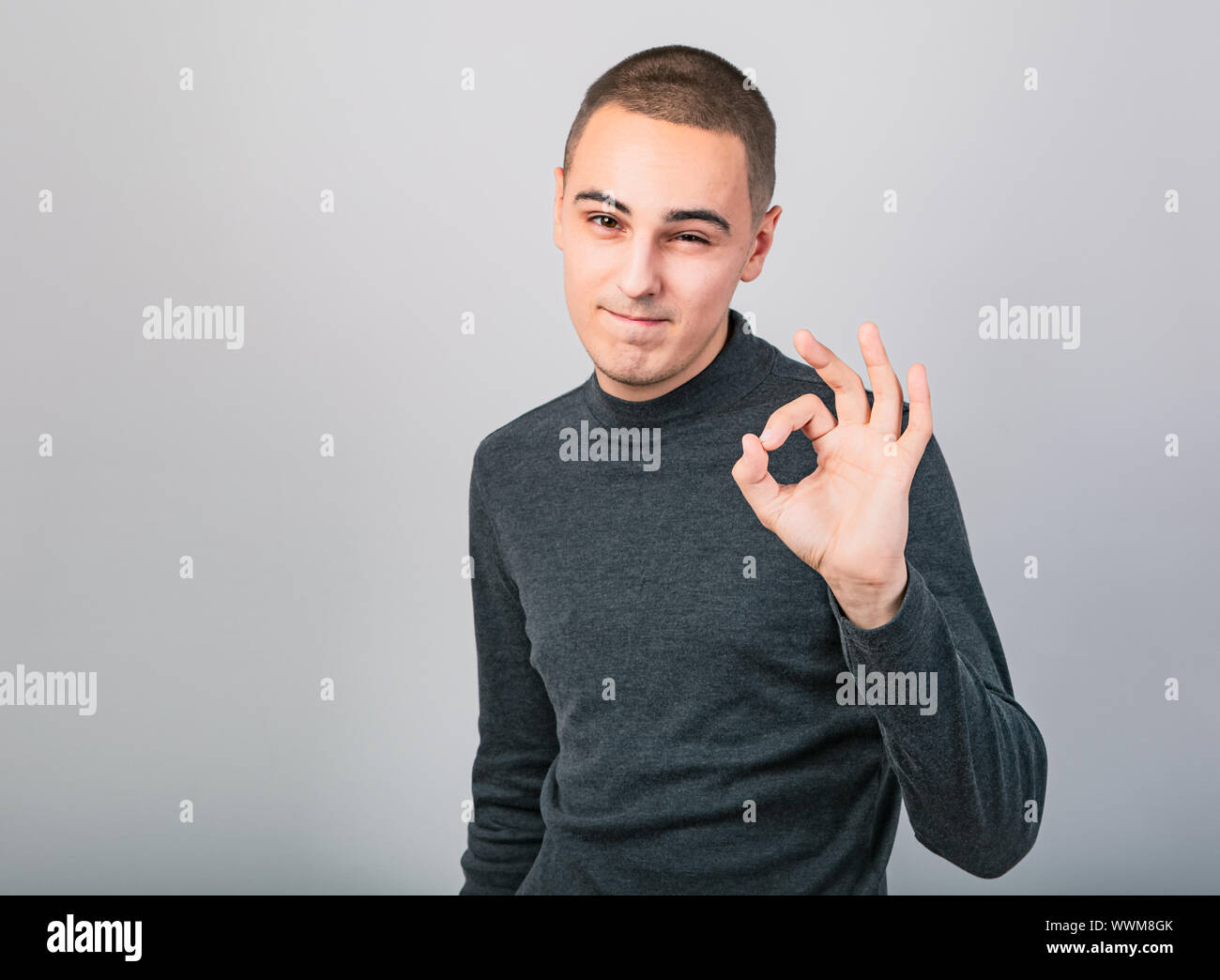 Happy smiling young man showing ok sign on blue background with empty ...