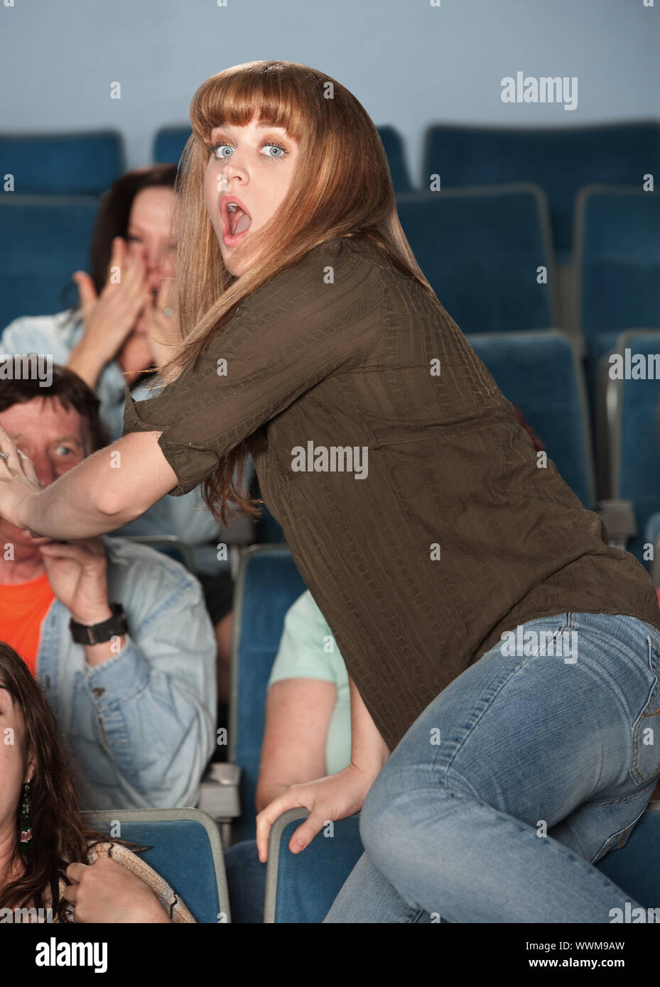 Scared young Caucasian woman jumps out of her seat in theater Stock ...