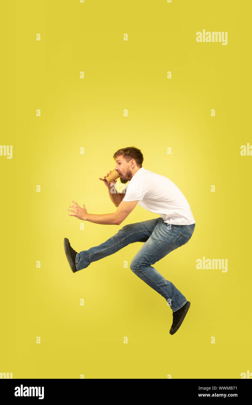 Full length portrait of happy jumping man isolated on yellow background ...