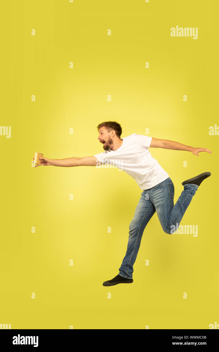 Full length portrait of happy jumping man isolated on yellow background ...