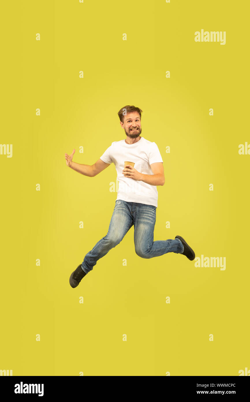 Full length portrait of happy jumping man isolated on yellow background ...