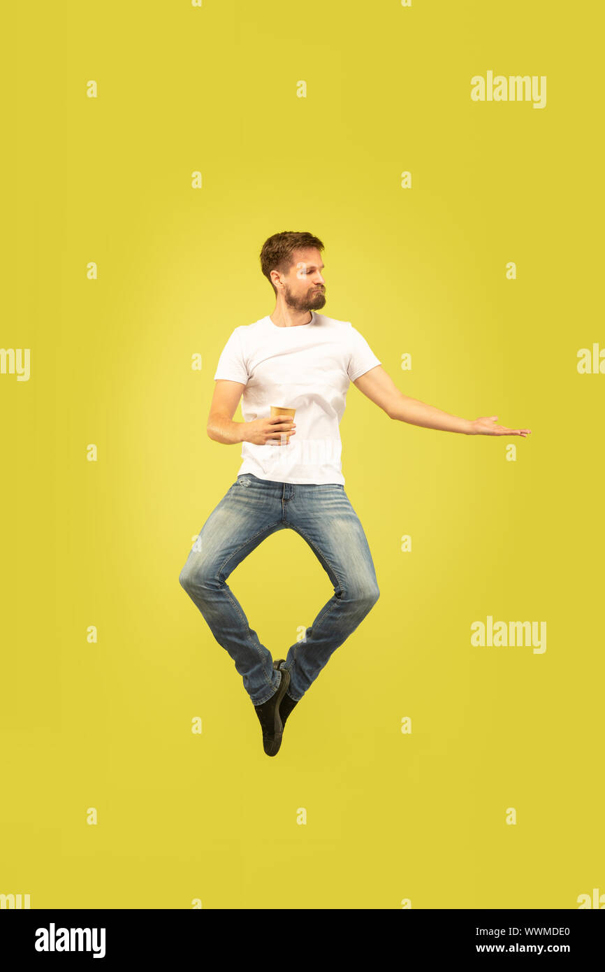 Full length portrait of happy jumping man isolated on yellow background ...
