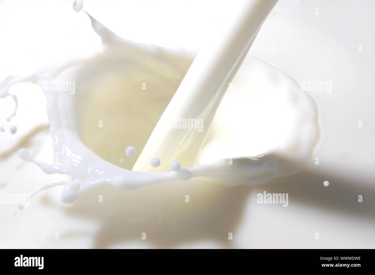milk splashes with many drops into fresh milk Stock Photo - Alamy
