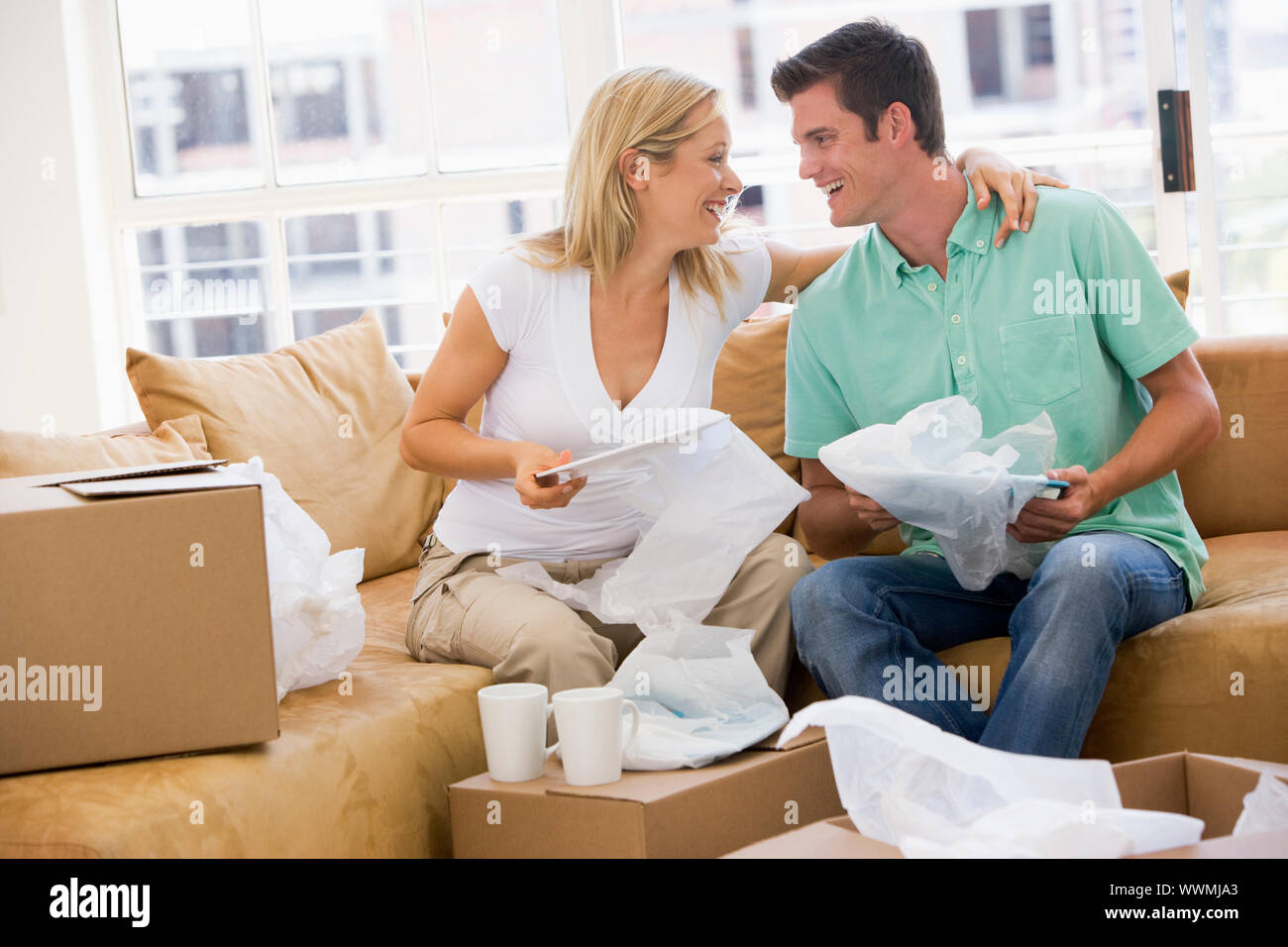Couple unpacking boxes in new home smiling Stock Photo - Alamy