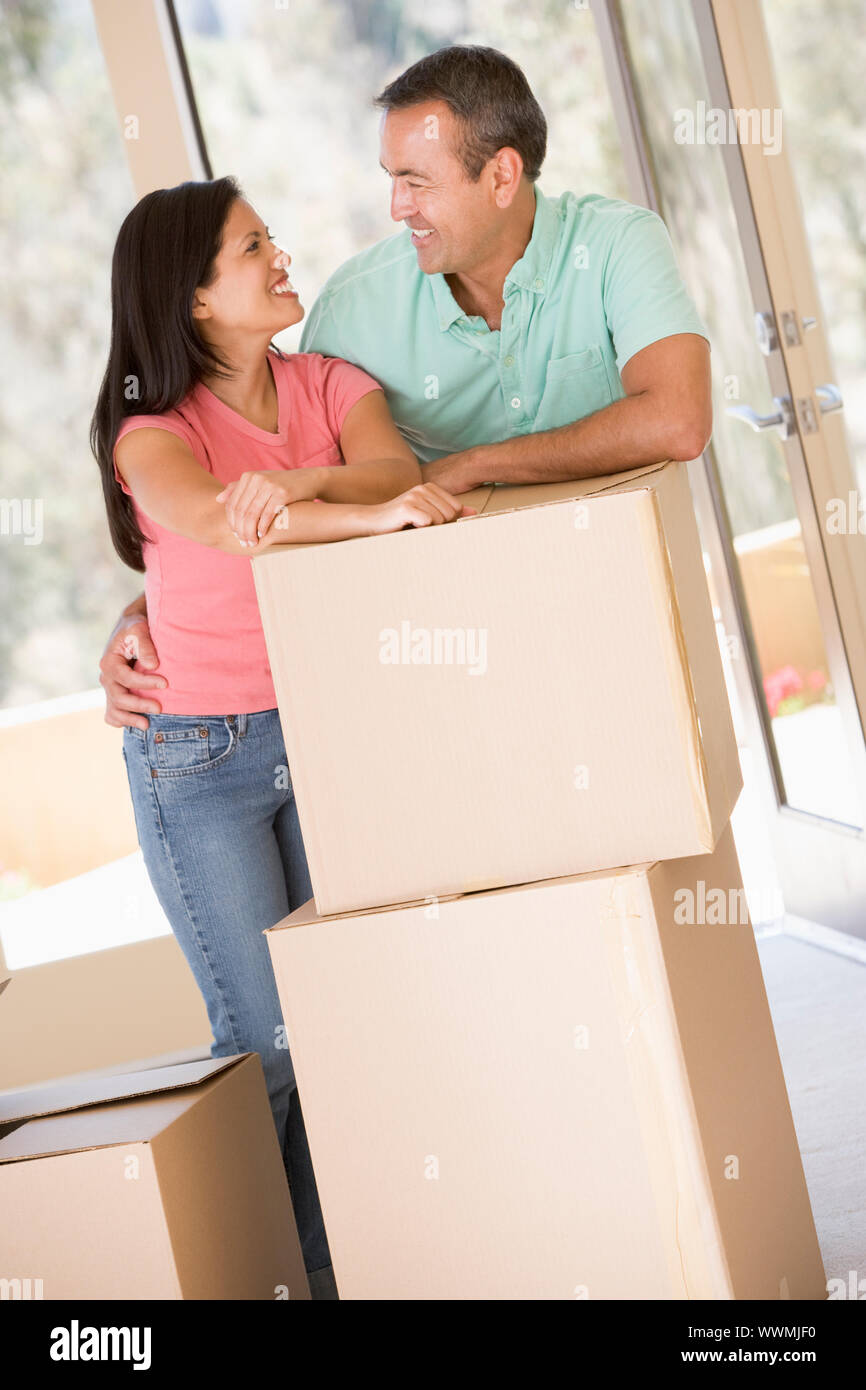 Couple with boxes in new home smiling Stock Photo - Alamy