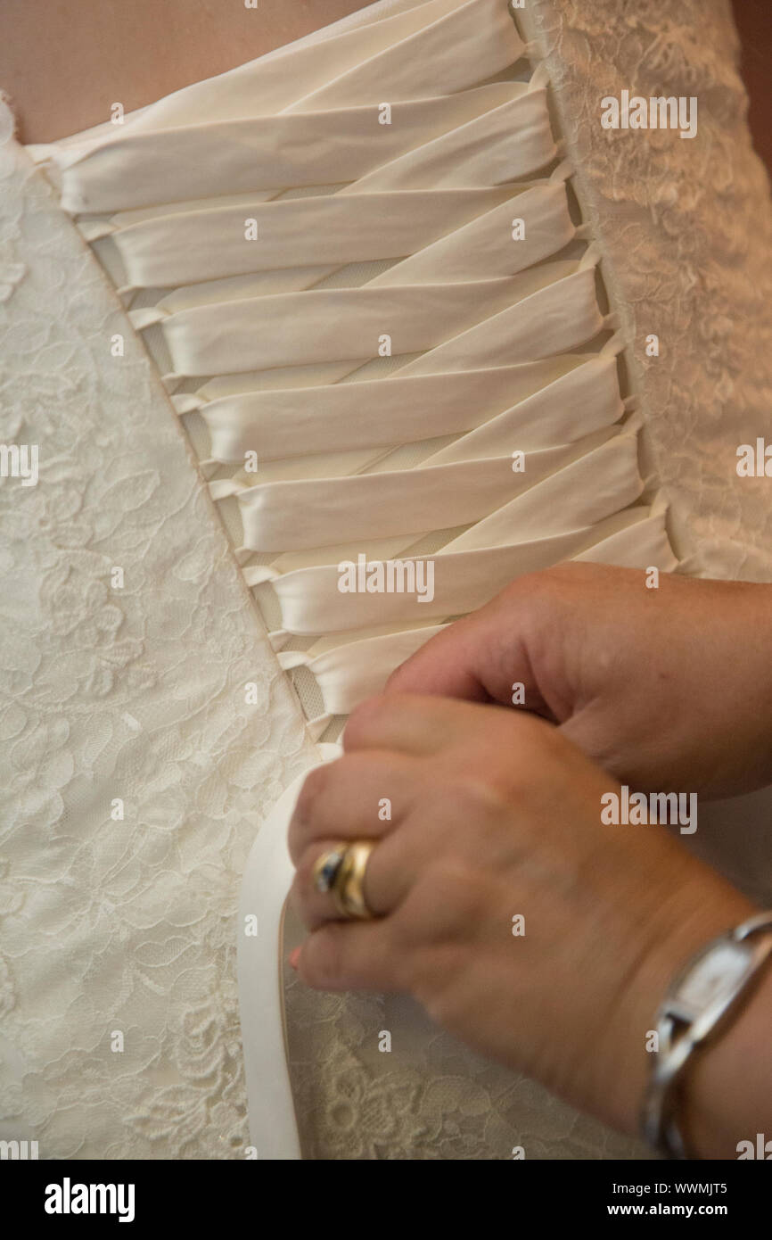 Brides dress being laced up on her wedding day by her mother just ...