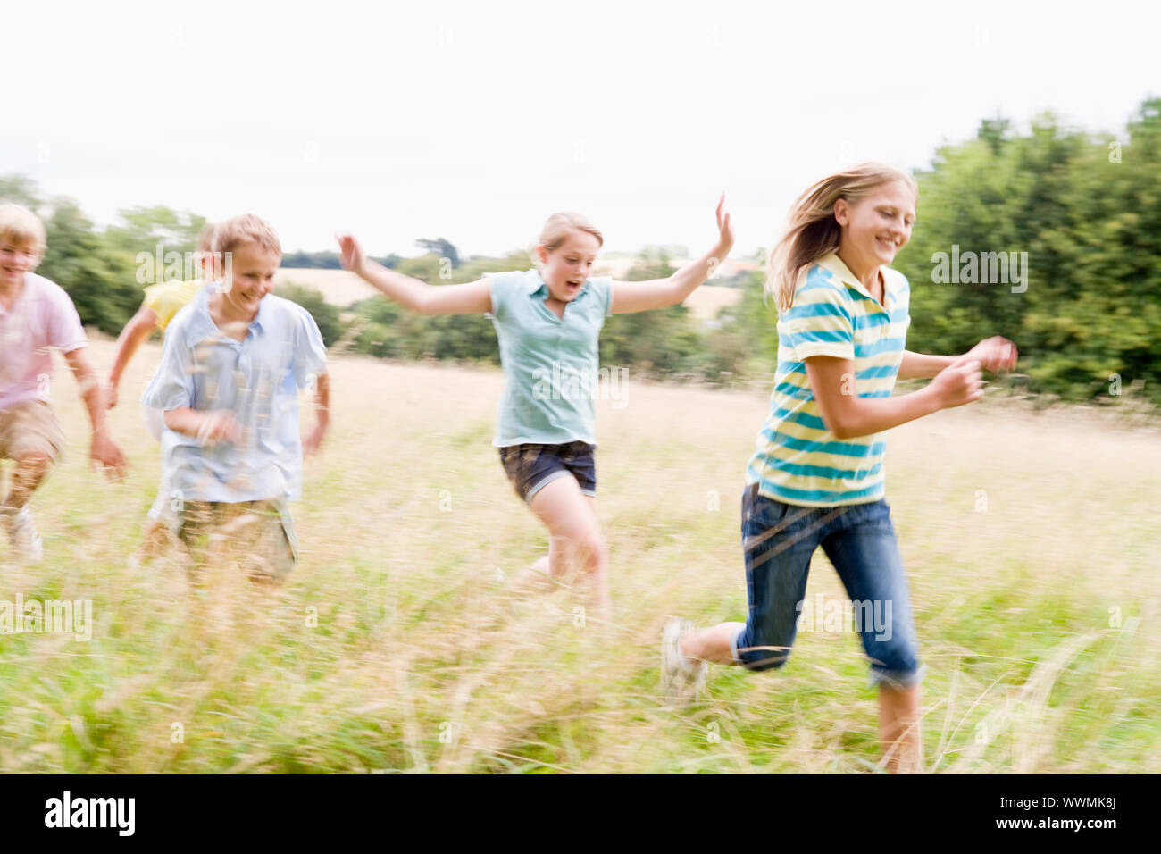 Five young friends running in a field smiling Stock Photo - Alamy