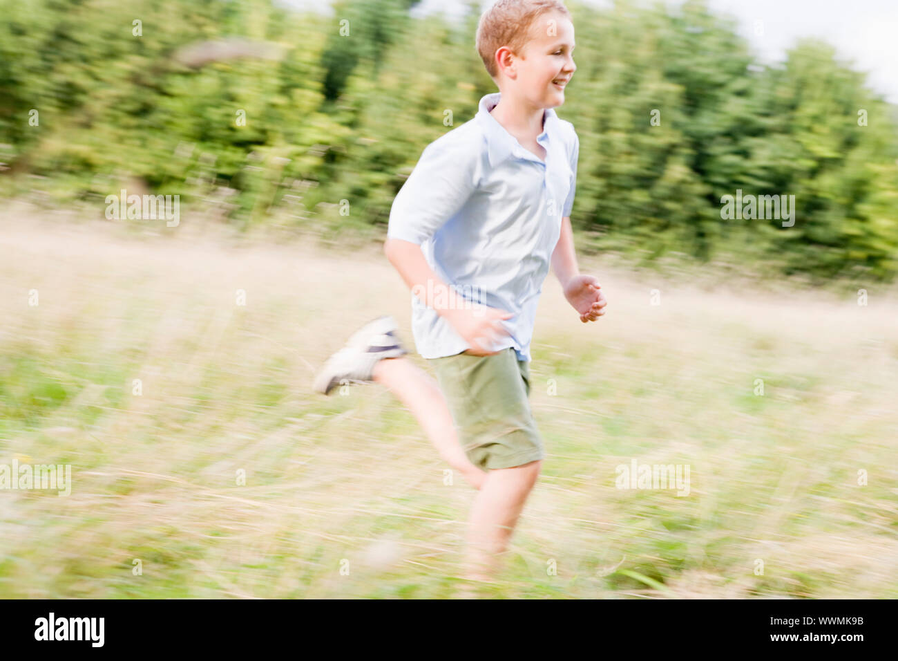 Young boy running in a field smiling Stock Photo - Alamy
