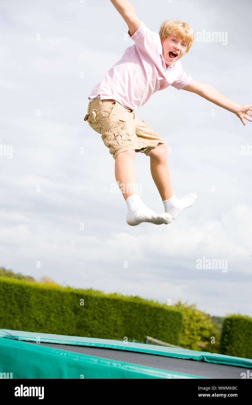 Young boy jumping on trampoline smiling Stock Photo - Alamy