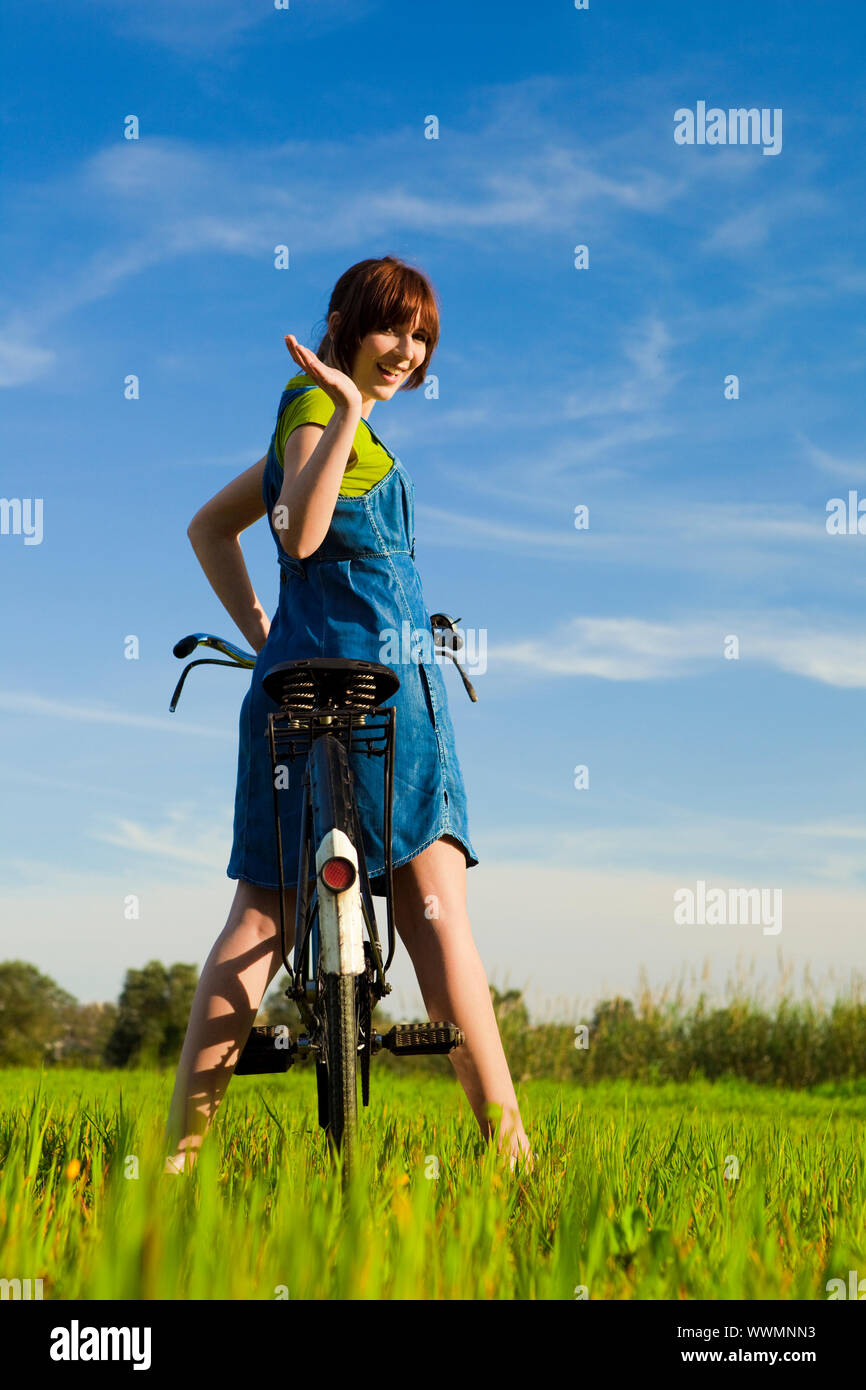 Happy girl over a bicycle and looking back and saying goodbye, in a ...