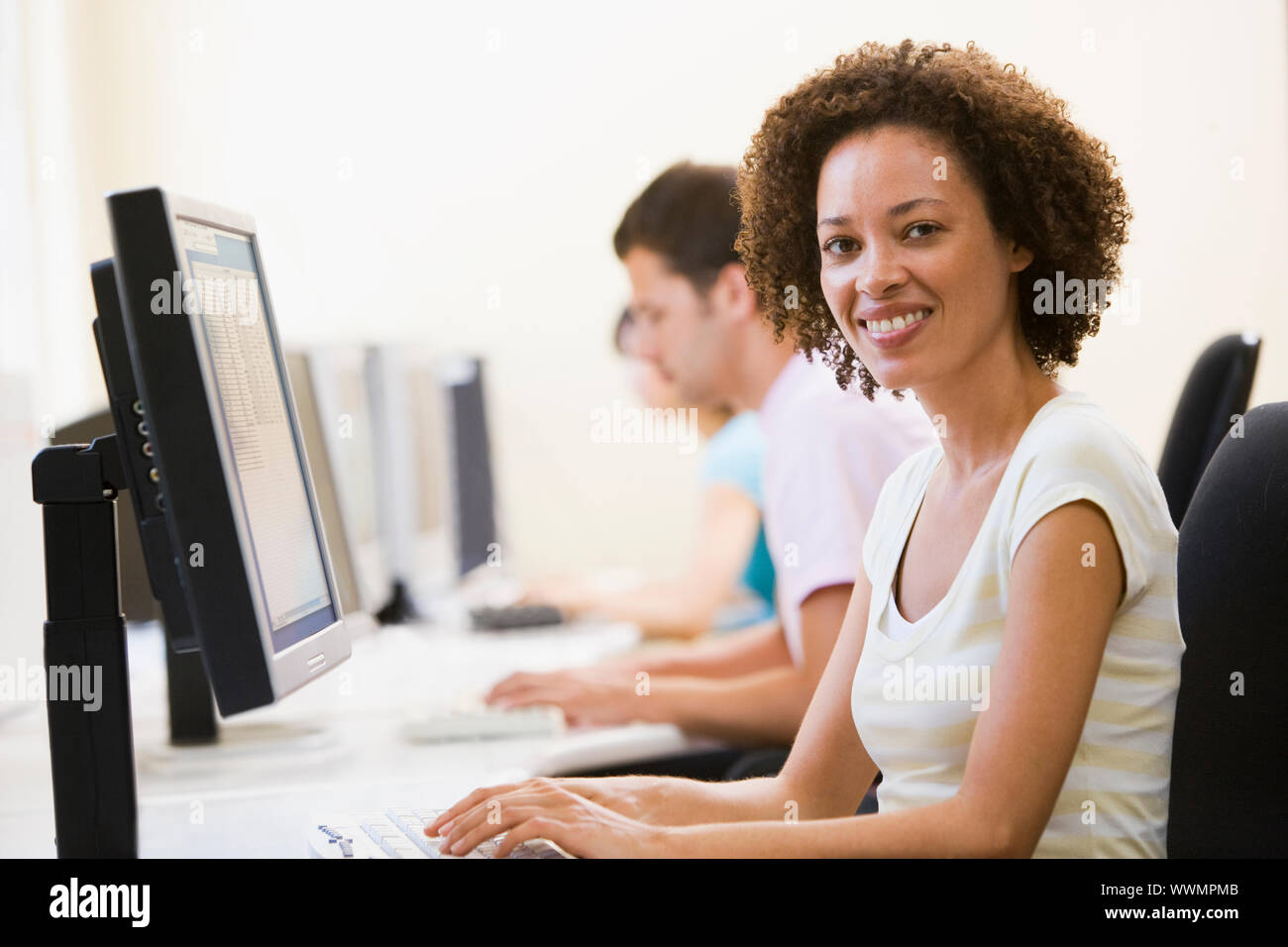 Three people in computer room typing and smiling Stock Photo - Alamy