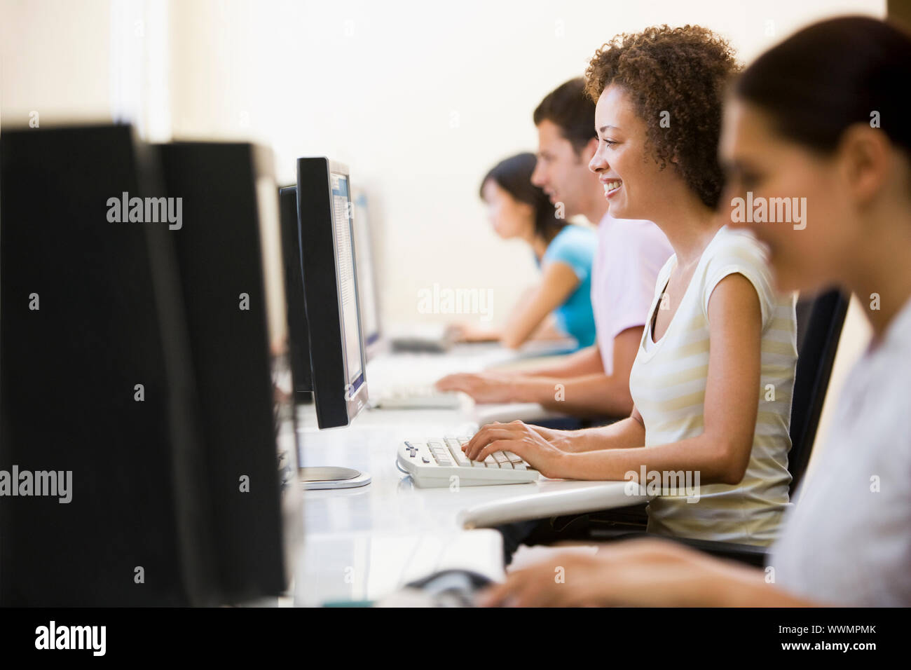 Four people in computer room typing and smiling Stock Photo - Alamy