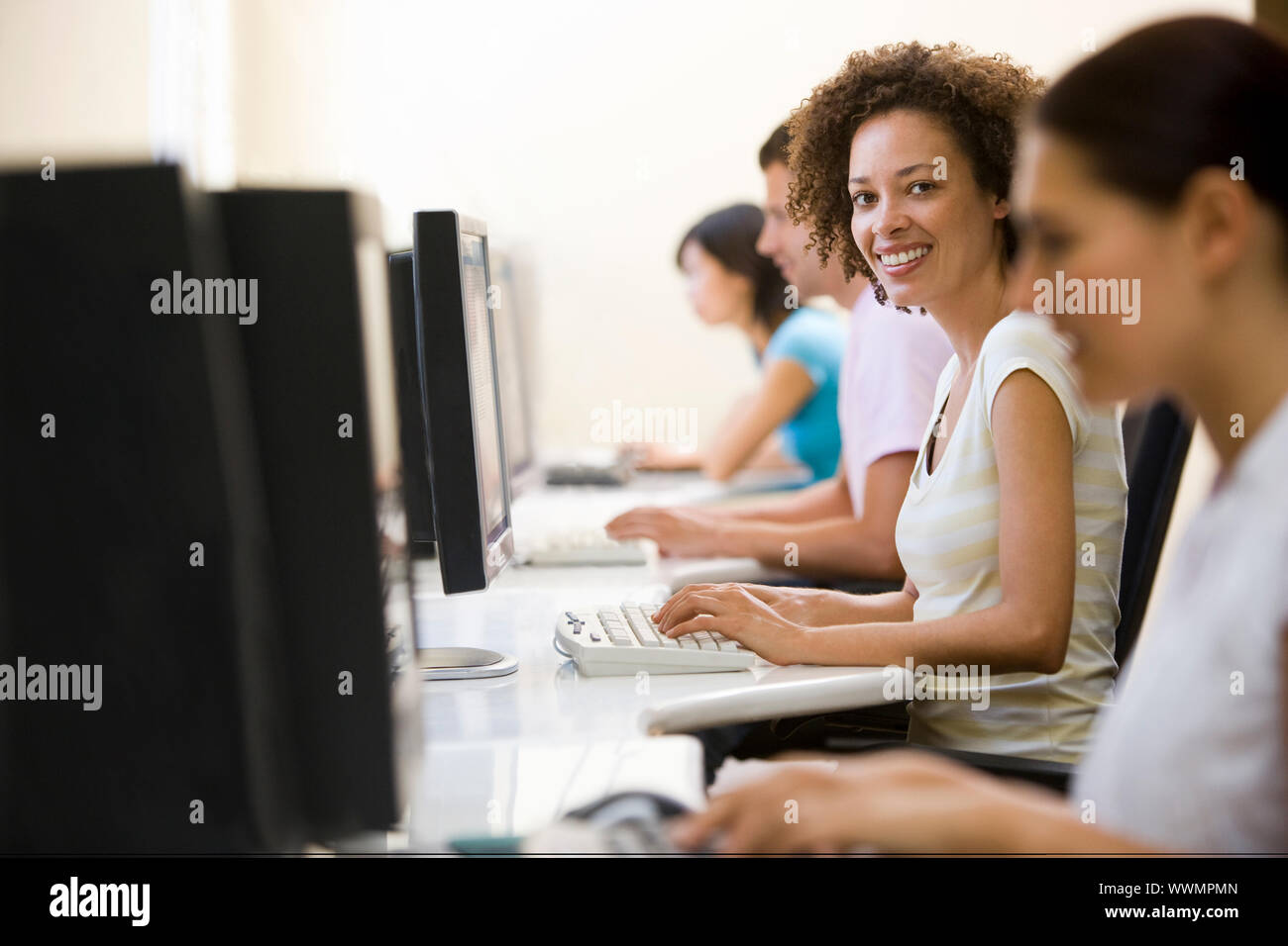 Four people in computer room typing and smiling Stock Photo - Alamy