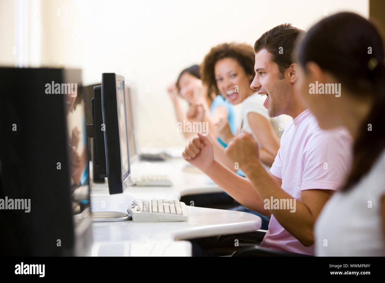Four people in computer room cheering and smiling Stock Photo - Alamy