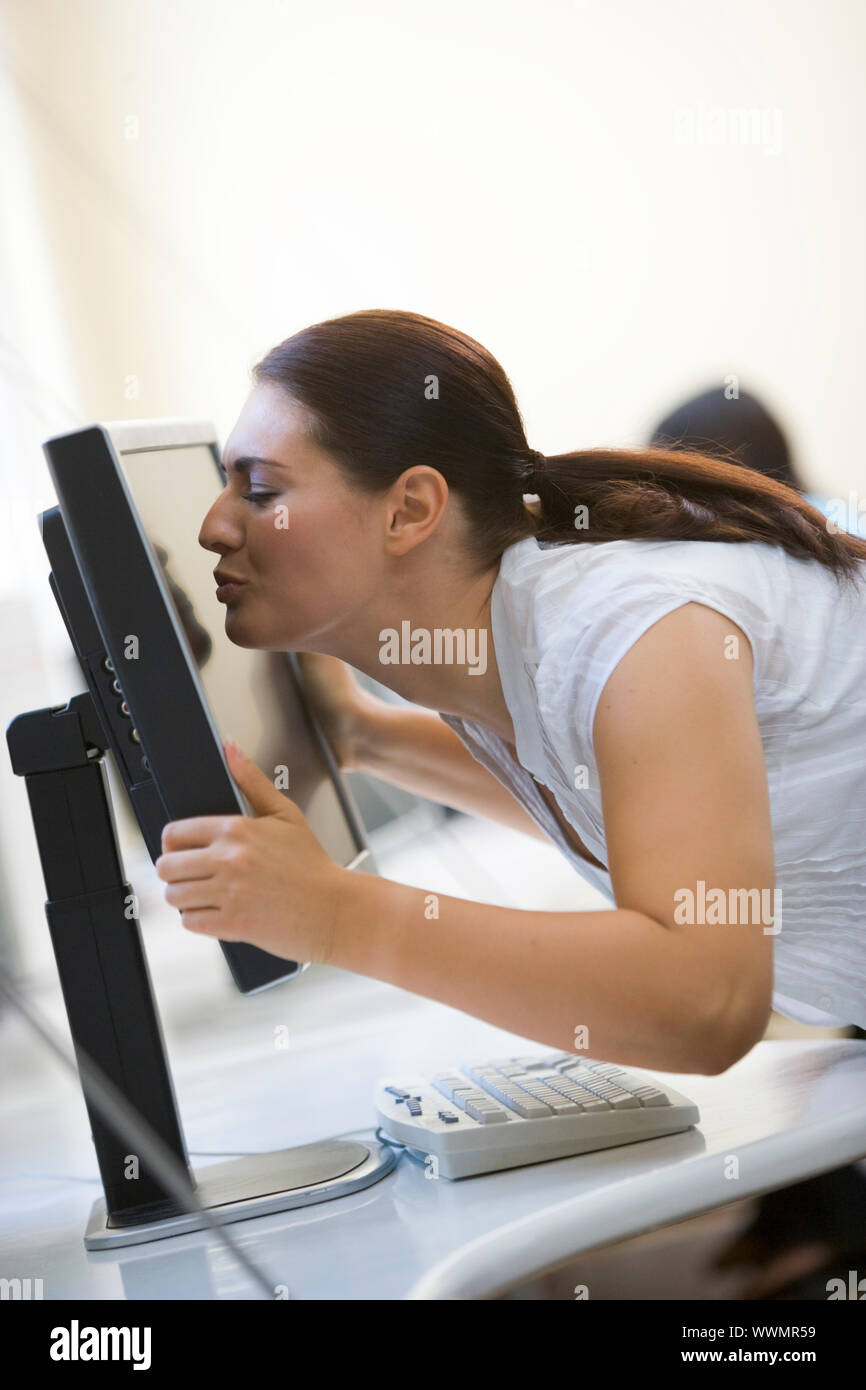 Woman in computer room kissing monitor Stock Photo - Alamy