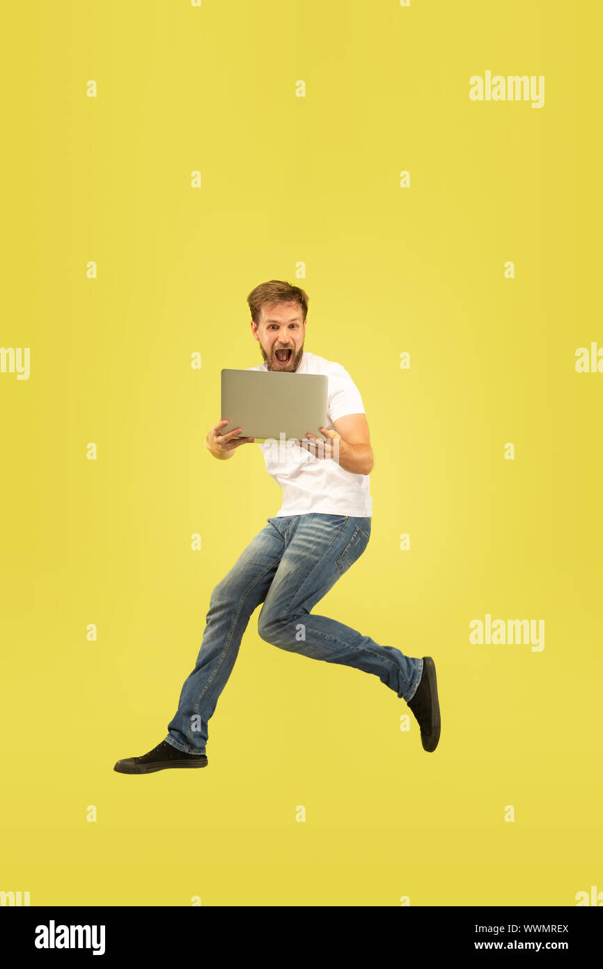 Full length portrait of happy jumping man isolated on yellow background ...