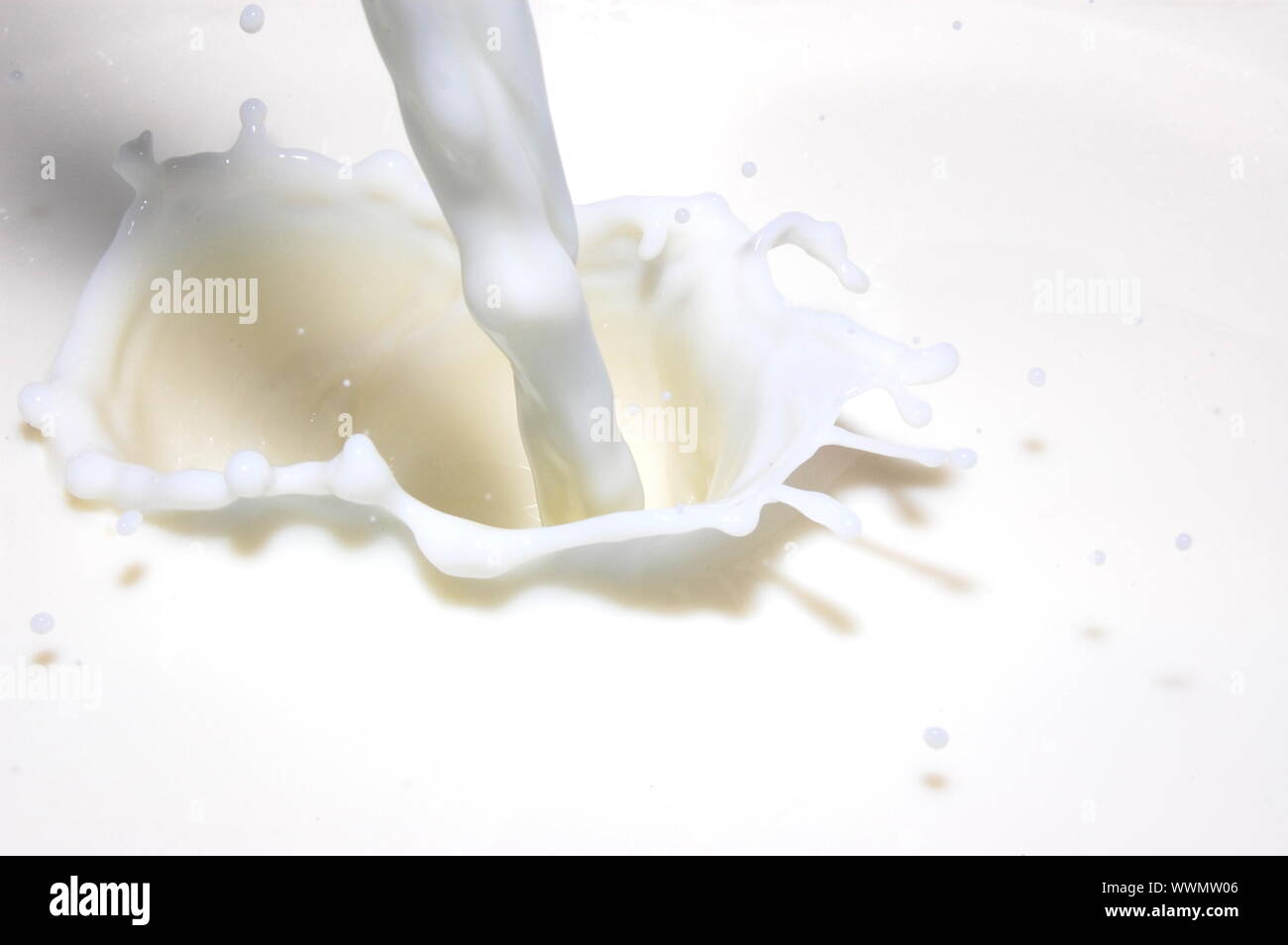 milk splashing into fresh milk with drops Stock Photo - Alamy