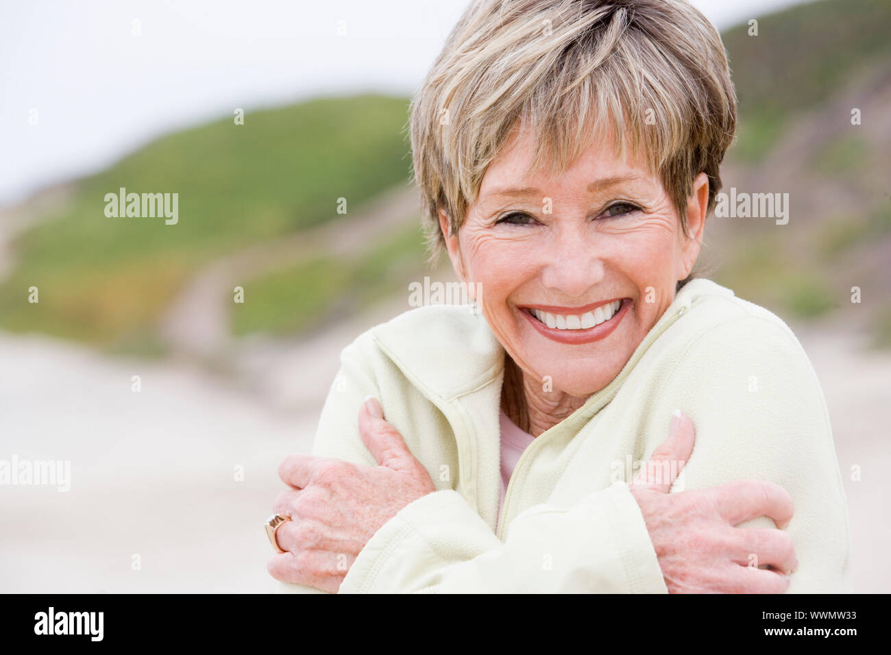 Woman at the beach cold and smiling Stock Photo - Alamy