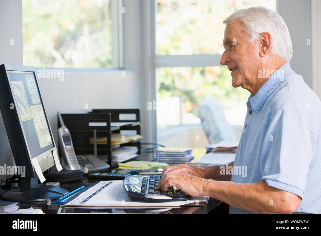 Man in home office using computer smiling Stock Photo - Alamy
