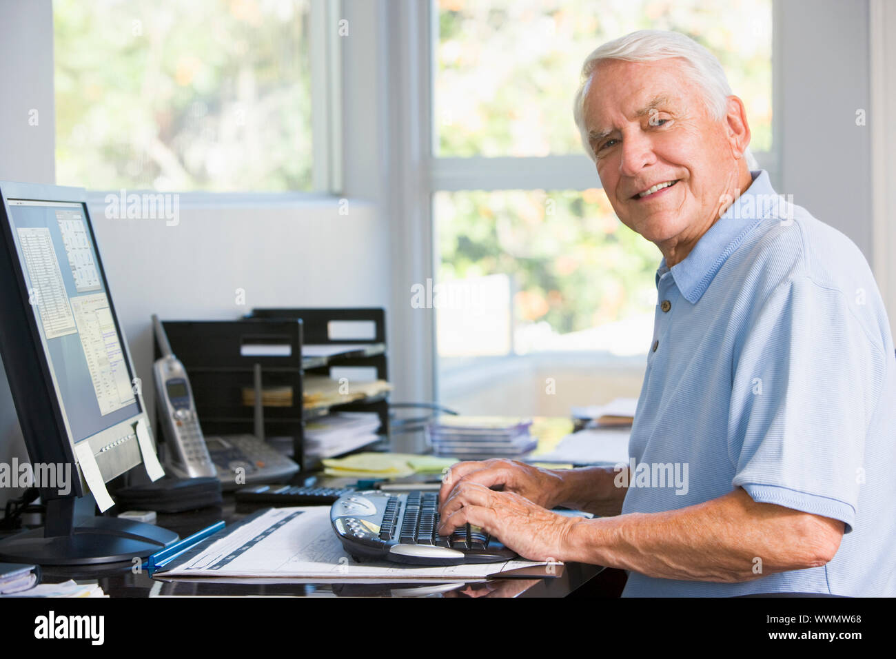 Man in home office using computer smiling Stock Photo - Alamy