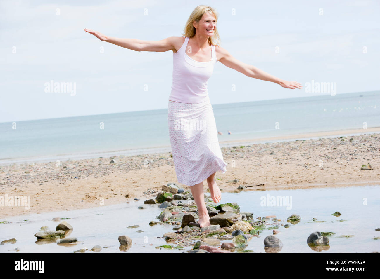 Woman walking on beach path smiling Stock Photo - Alamy