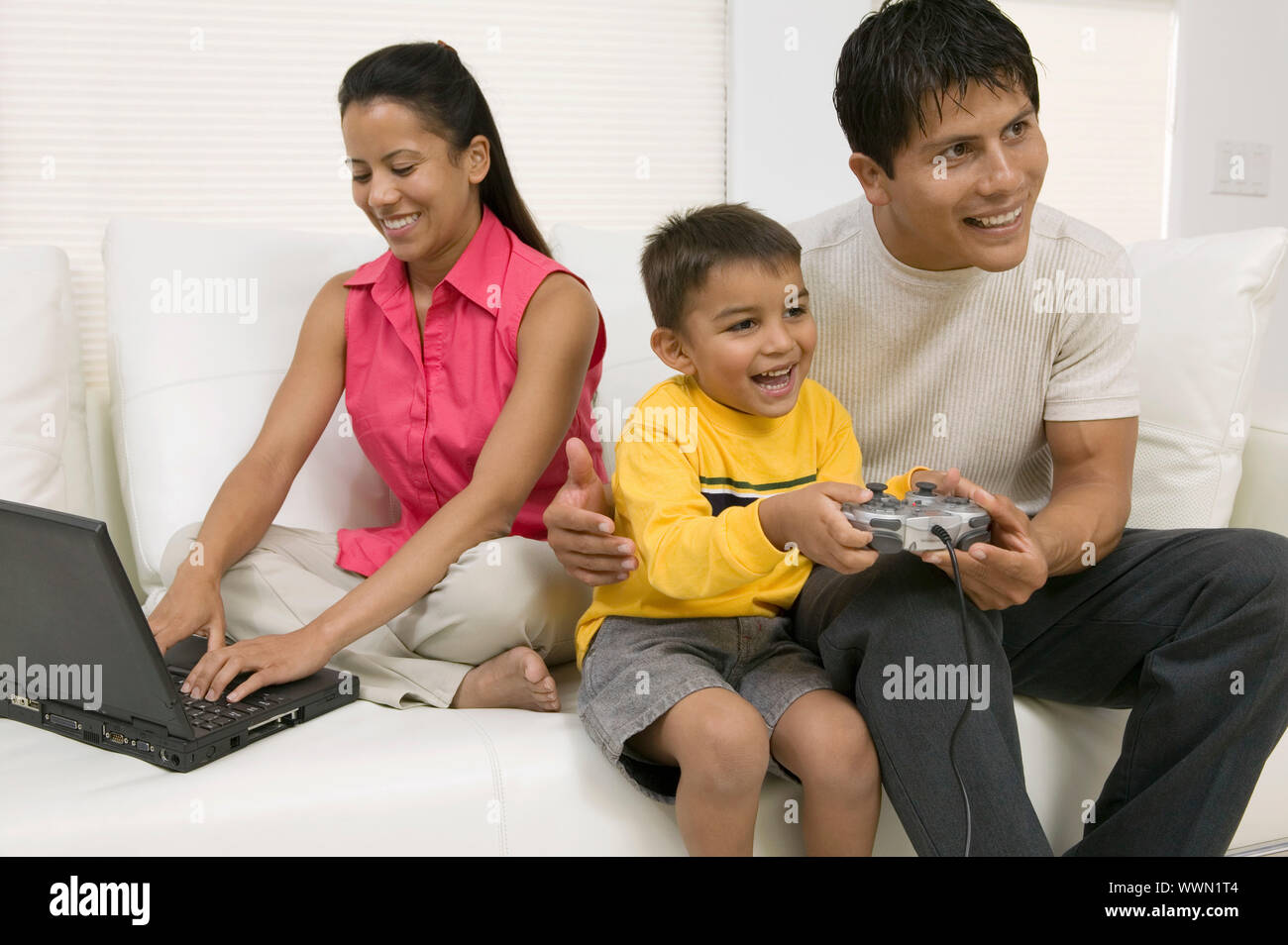 Family Playing Video Game and Using Computer on Couch Stock Photo - Alamy