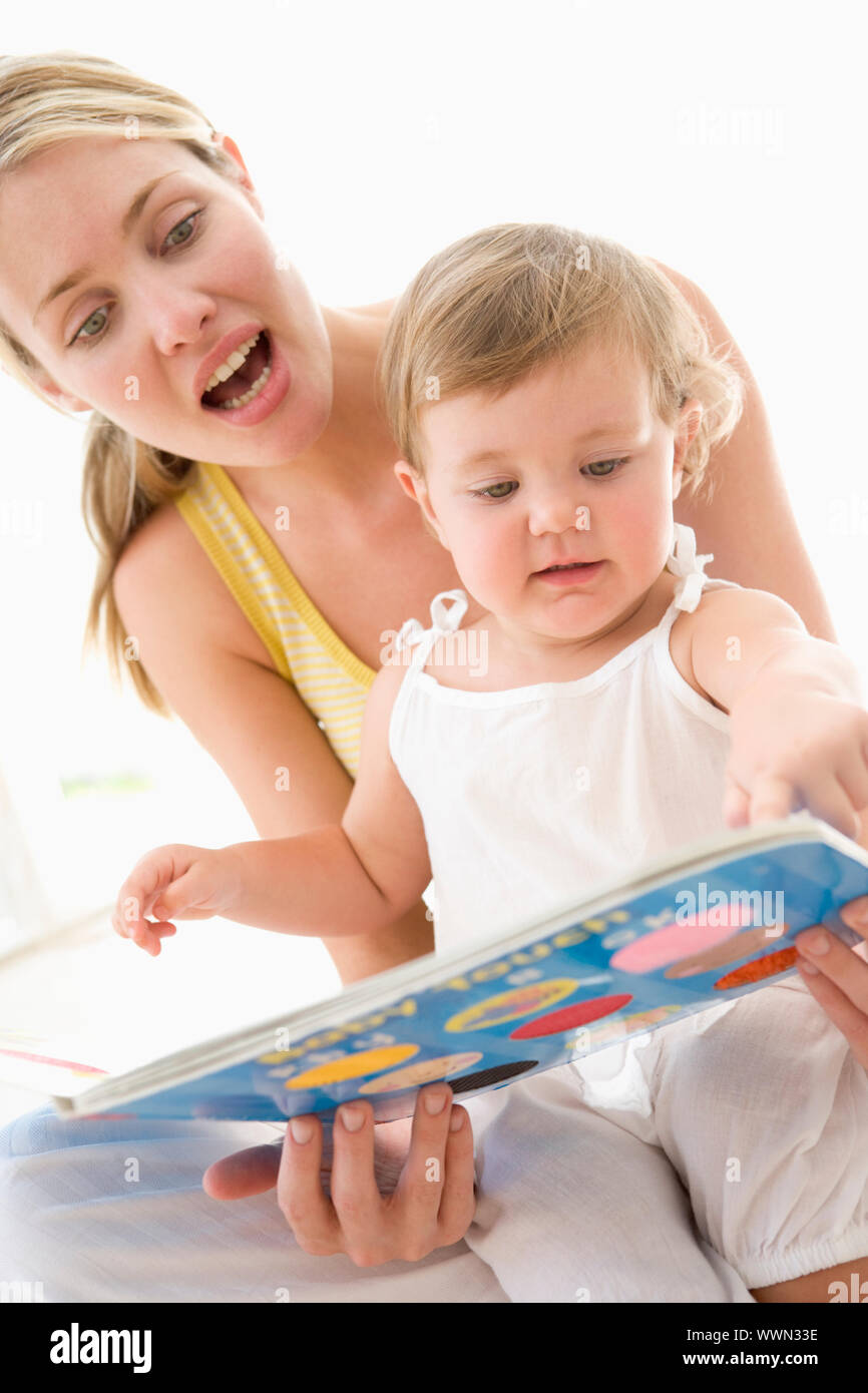 Mother and baby reading book indoors and pointing Stock Photo - Alamy