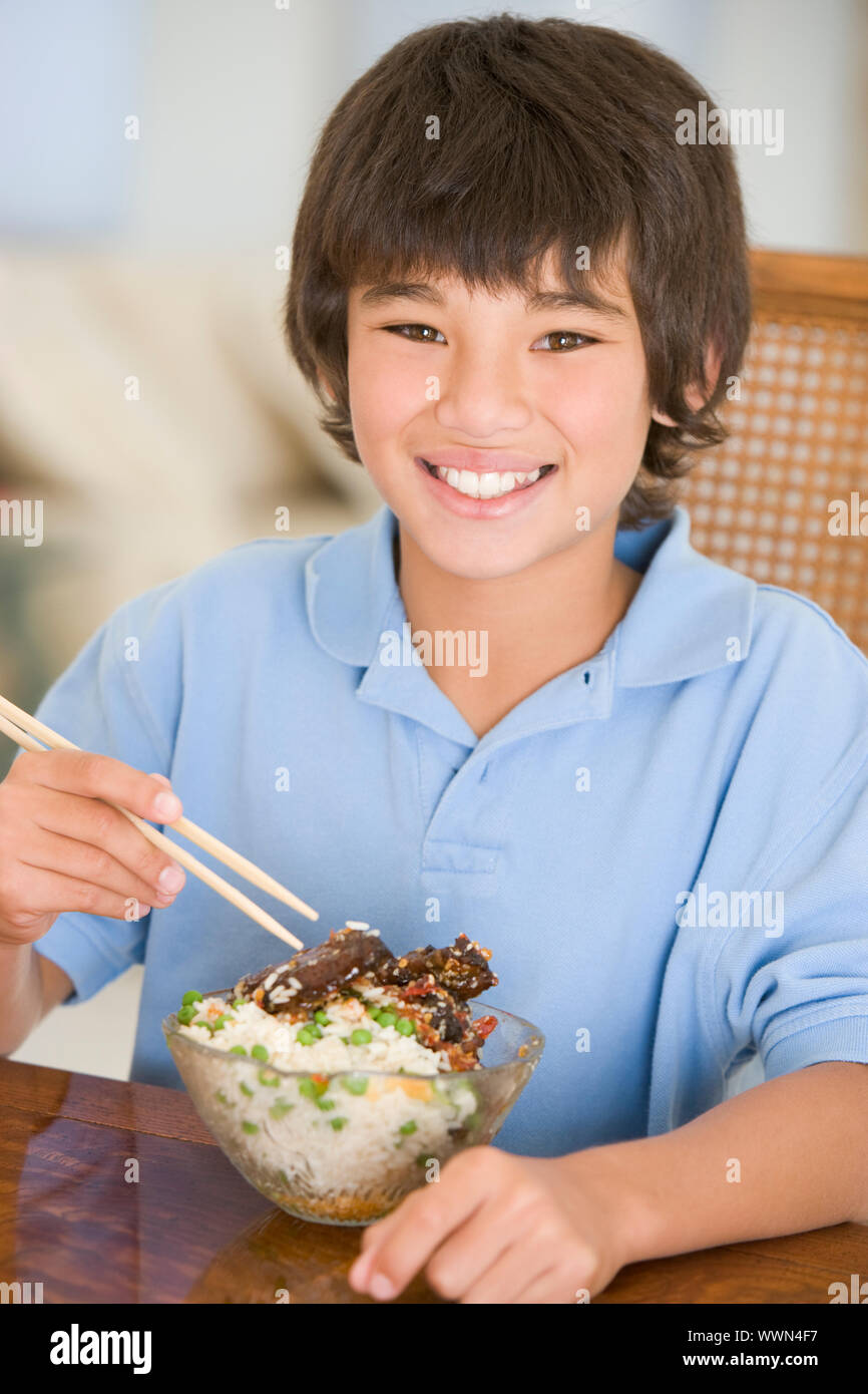 Young boy in dining room eating chinese food smiling Stock Photo - Alamy
