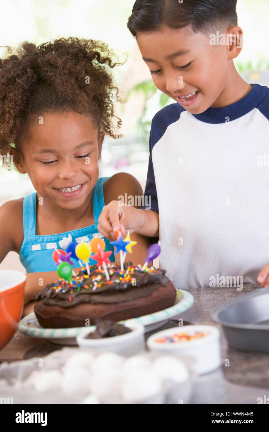 Two children in kitchen with birthday cake smiling Stock Photo - Alamy