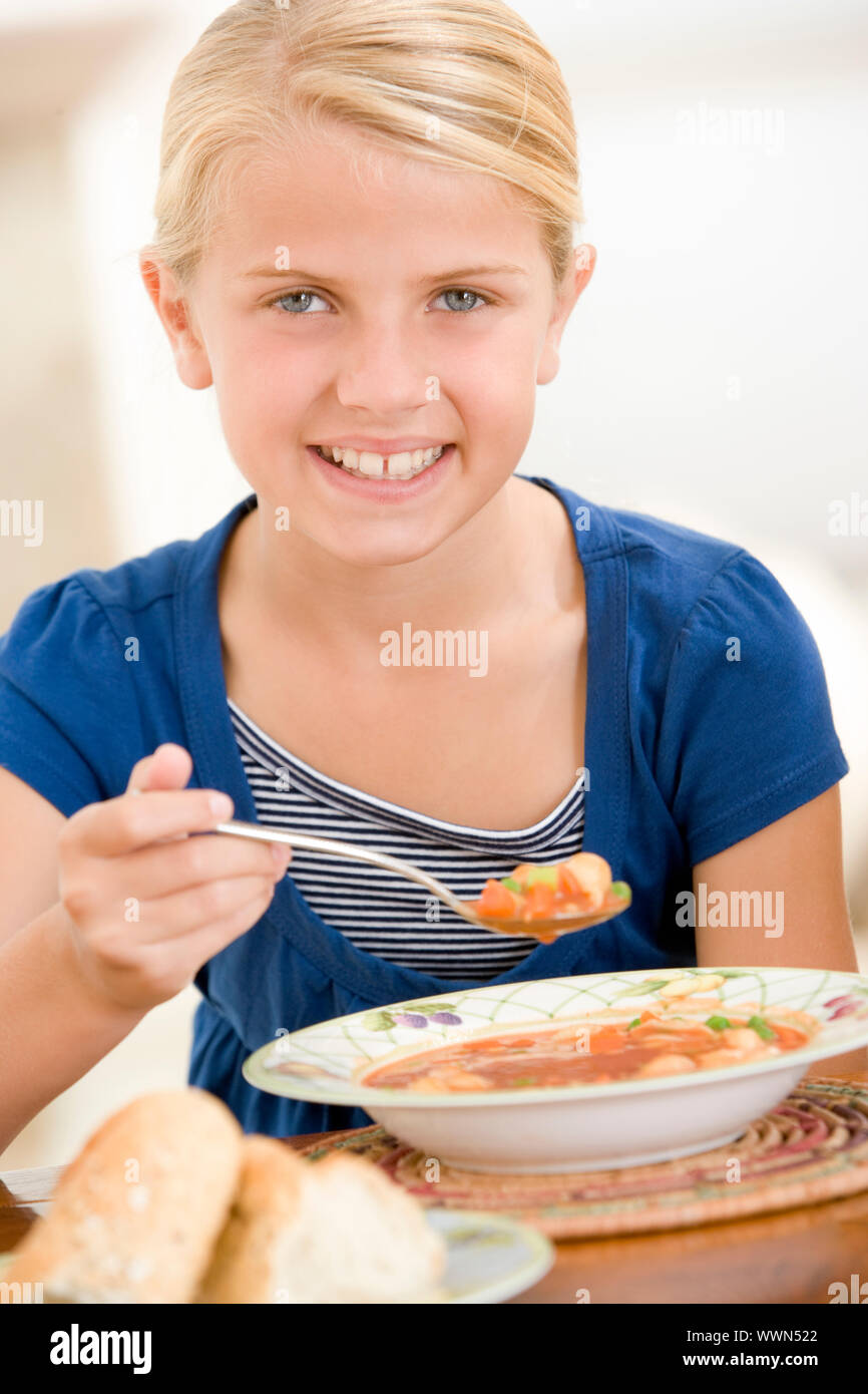 Young girl indoors eating soup smiling Stock Photo - Alamy