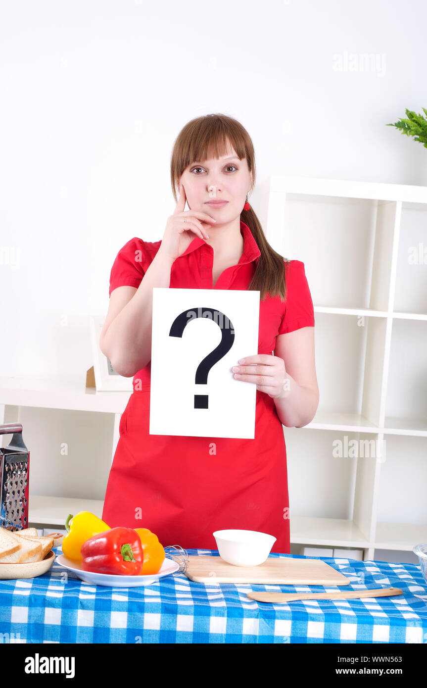 Young woman cooking fresh meal at home and holding question sign Stock ...