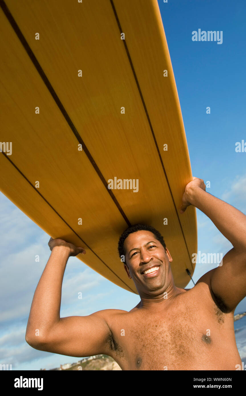 Man Carrying Surfboard on Head Stock Photo - Alamy