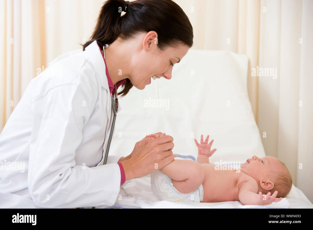 Doctor giving checkup to baby in exam room smiling Stock Photo - Alamy